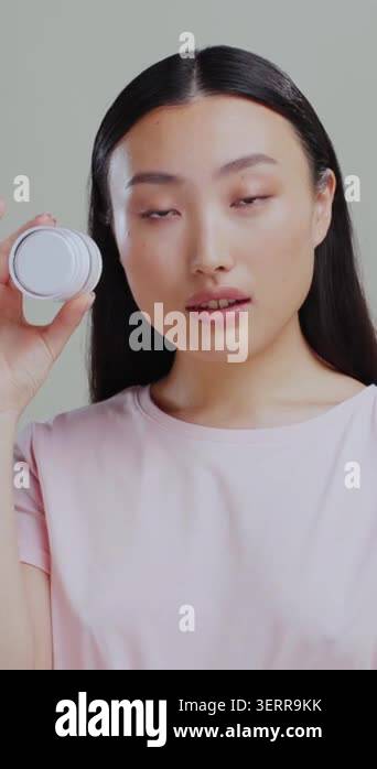 Young attractive asian woman holding cosmetic products showing at ...