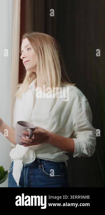 Charming happy young woman drinking coffee at home enjoying relaxed ...