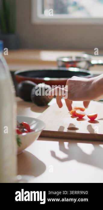 Close up woman after a shower in grey coat cooking cut tomato in the ...