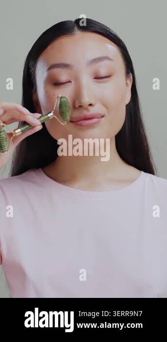 Young attractive japanese woman in grey studio background doing gentle ...