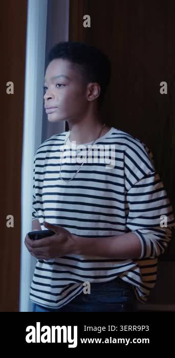 Beautiful young african american woman stand near window using ...