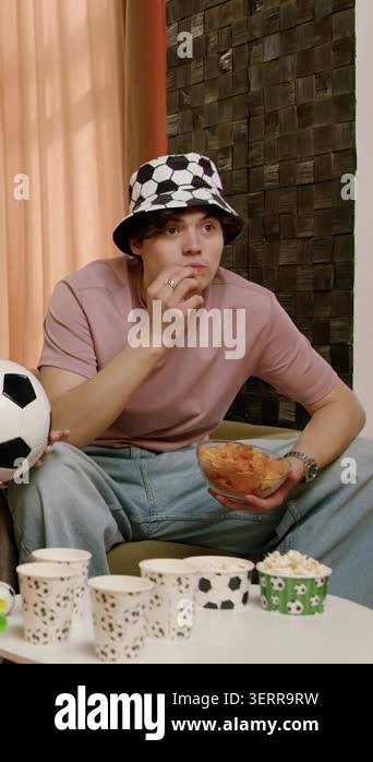 Young man in a checkered bucket hat enjoys snacks from a bowl while ...