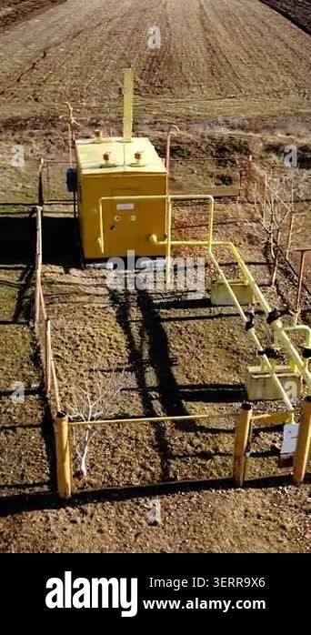 Yellow control box with visible piping and fencing in a rural landscape ...