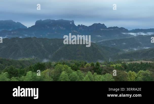 Aerial drone footage captures a vast, misty mountain range with lush ...