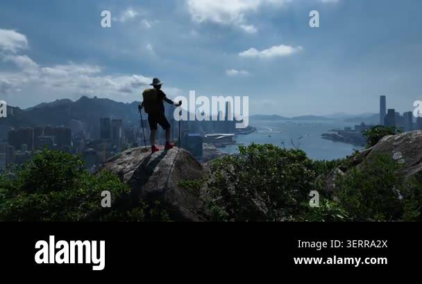 A lone hiker stands on a rocky outcrop, looking out at a sprawling ...