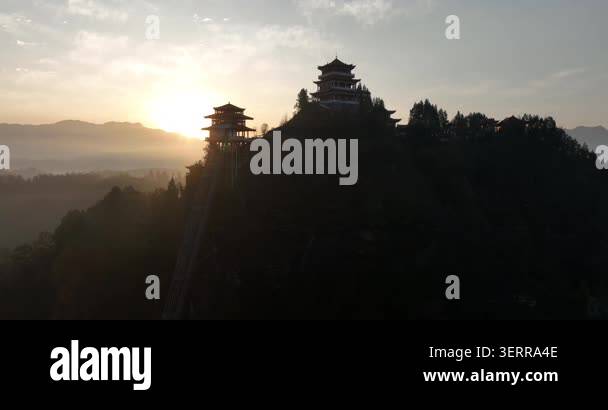 Sunrise over a traditional Asian temple complex perched on a misty ...