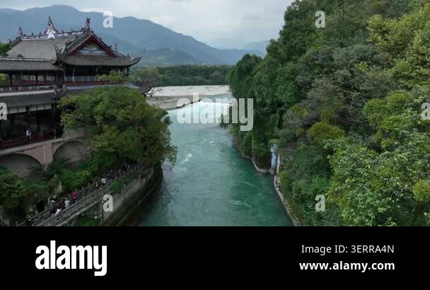 Aerial view of a wide river flowing past lush green trees and a ...