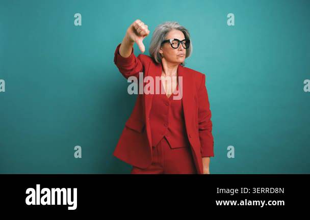 Disappointed senior businesswoman in a red suit expressing disapproval ...