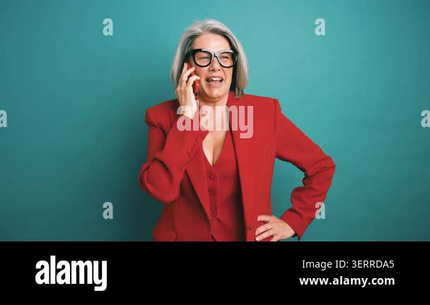 Stylish senior businesswoman with grey hair in a red suit having a ...