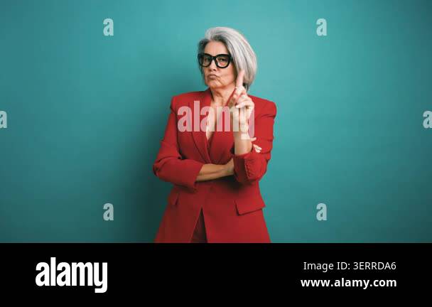 Confident mature woman with grey hair in a red suit making a scolding ...