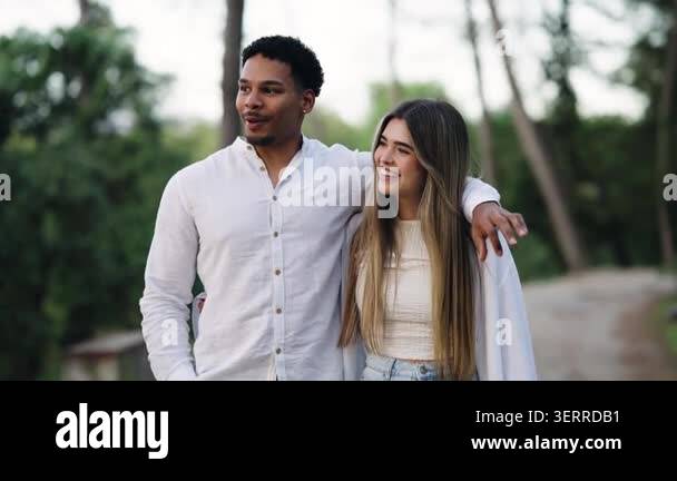 Happy young interracial couple enjoying a romantic walk together. The ...