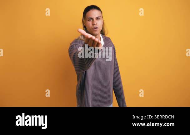 Handsome long haired man sending a kiss and showing a heart shape with ...