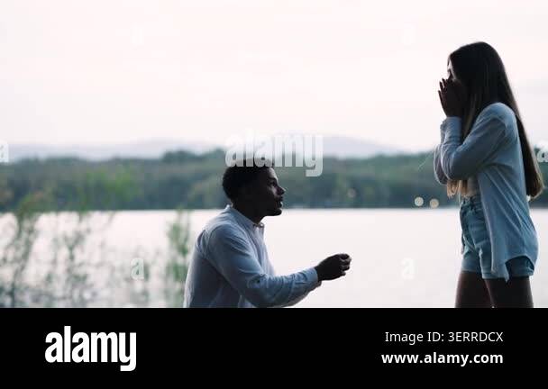 Young man getting down on one knee and asking his girlfriend to marry ...