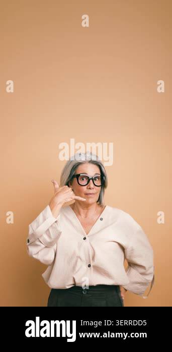 Elegant mature woman with grey hair and glasses smiling and gesturing ...