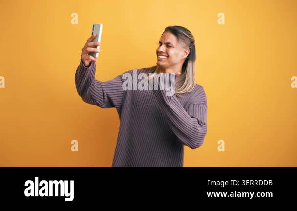 Cheerful young man with long hair taking a selfie or having a video ...