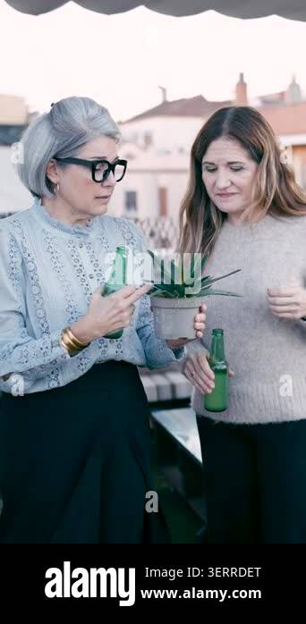 Two women, a mother and her adult daughter, chatting and laughing ...