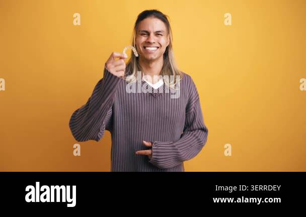 Young handsome man with a charming smile holding and pointing at his ...