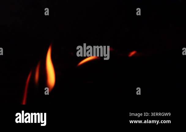 Close-up of bright orange flames dancing against a dark background ...