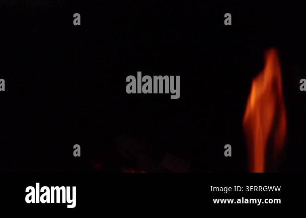 Abstract close-up of a glowing orange flame against a dark black ...