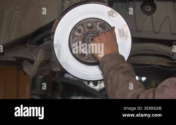 Close up shot of auto mechanic hands replacing a shiny new brake disc ...