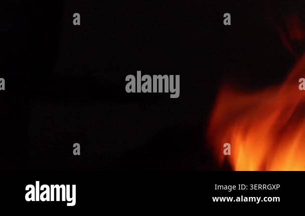 Minimal close-up of a glowing orange flame against a dark black ...