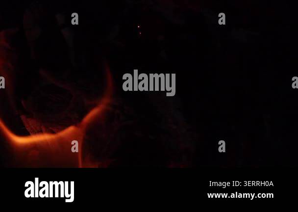 Close-up of soft orange flames moving through darkness, creating an ...