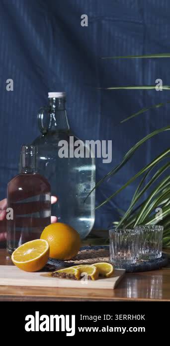 Man pouring clear mezcal from a glass bottle into a drinking glass ...