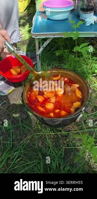 Close-up of a person using a ladle to serve hot Hungarian bogracs ...