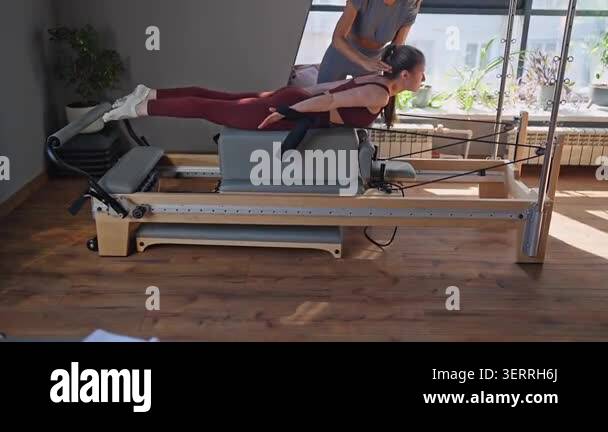 Woman doing Swan exercise on Pilates Reformer for the chest and back ...