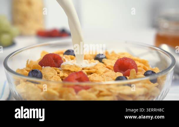 Fresh milk pouring with splash into cornflakes with raspberry and ...