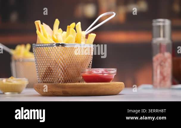 Crispy french fries served in metal basket being dipped into tomato ...