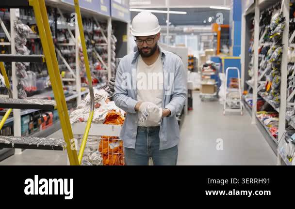 Warehouse worker putting on gloves before climbing ladder Stock Video ...
