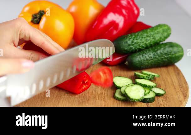Close-up of a chef slicing a red bell pepper on a wooden board. Fresh ...
