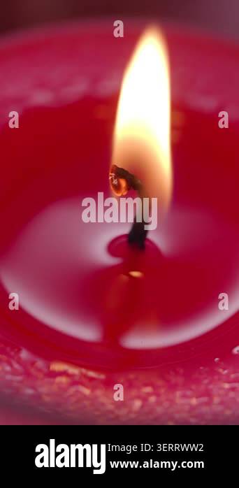 A candle flame burns steadily in red wax at a close distance Stock ...