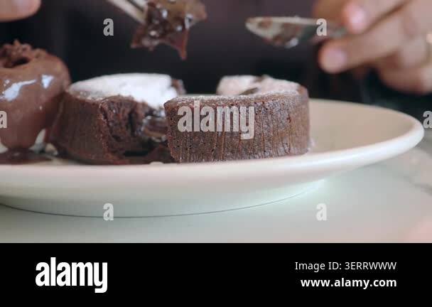 People eat a chocolate dessert at a cafe. The dish has warm chocolate ...