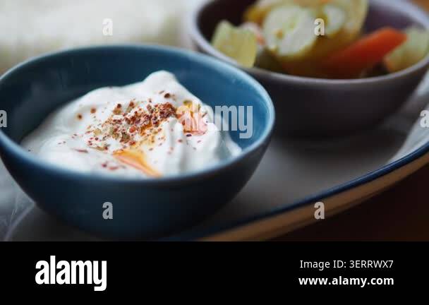 Dishes feature yogurt with spices and a side of pickled vegetables atop ...