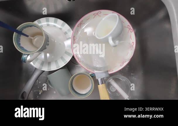 A person washes dirty dishes in a kitchen sink full of water Stock ...