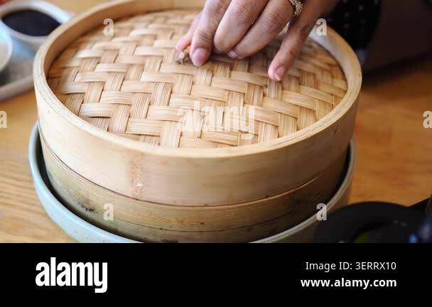 Dumplings are placed in a bamboo steamer for cooking in the kitchen ...