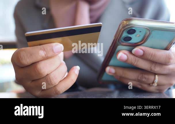 Person is using a phone while holding a credit card in a cafe Stock ...