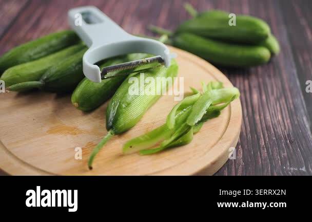 Cucumbers are cut and peeled on a wooden surface in a kitchen Stock ...