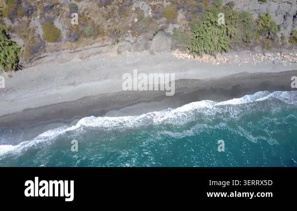 Aerial drone view flying backwards from the turquoise sea to reveal ...