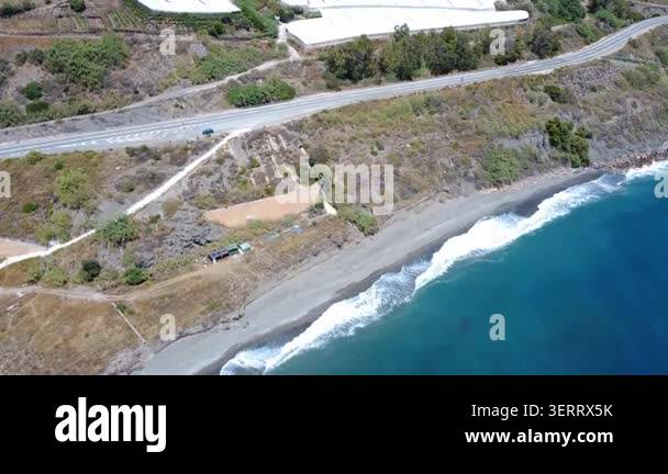 Aerial footage capturing a coastal road alongside a beautiful beach ...