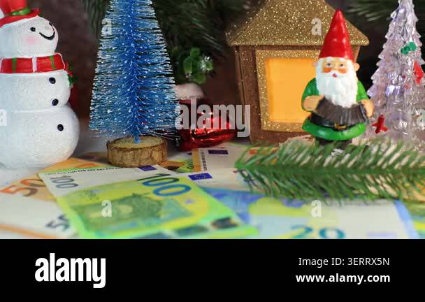 A gnome with a Christmas tree branch and euro banknotes against a ...