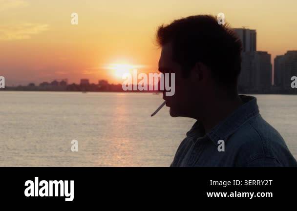 Man is Smoking Cigarette near the Sea in Sunset Stock Video Footage - Alamy