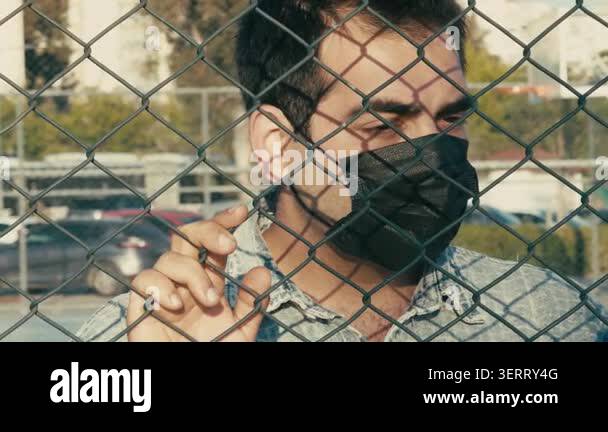 Young Man with Protection Mask Standing Sad Behind the Metallic Fence ...