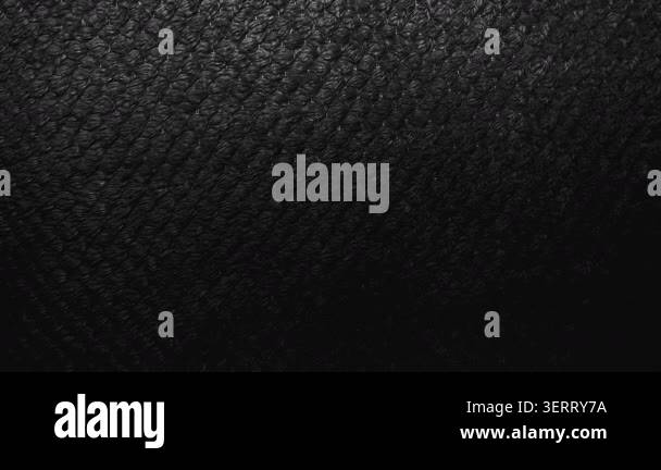 cinematic macro pan shifts light across dark black textured knit fabric ...