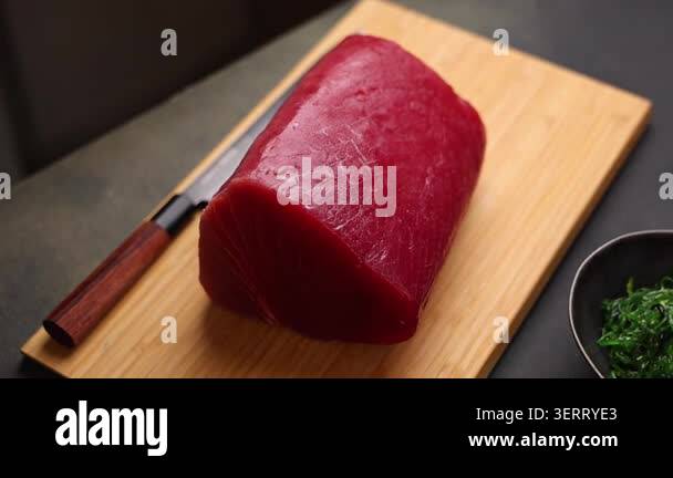 Close-up of a chef slicing fresh tuna on a wooden cutting board Stock ...