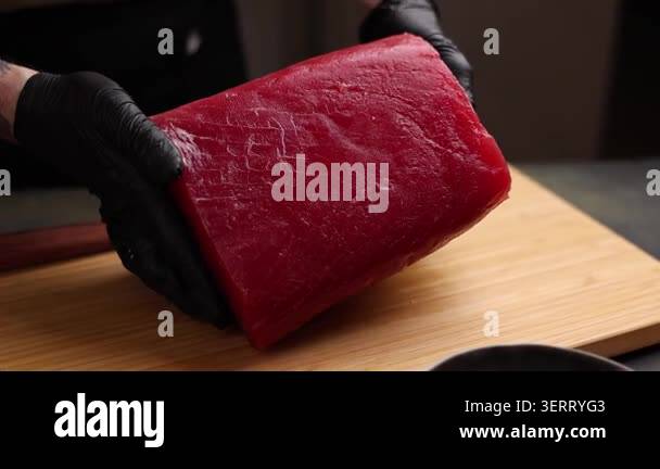 Close-up of a chef slicing fresh tuna on a wooden cutting board Stock ...