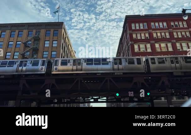 A train moves on elevated tracks above a busy street in the city. Two ...
