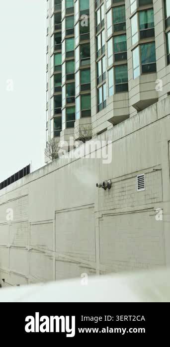 Water flows from a system on a wall near a tall building in a city. The ...